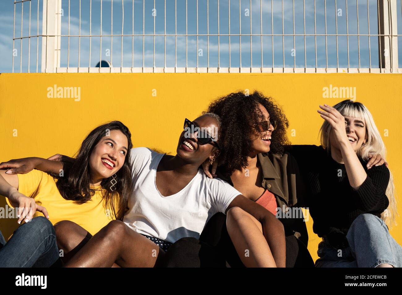 Cheerful young multiracial female students enjoying pastime on stadium ...