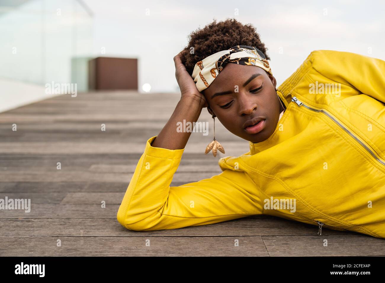 Stylish African American female in modern jacket relaxing lying down on ...