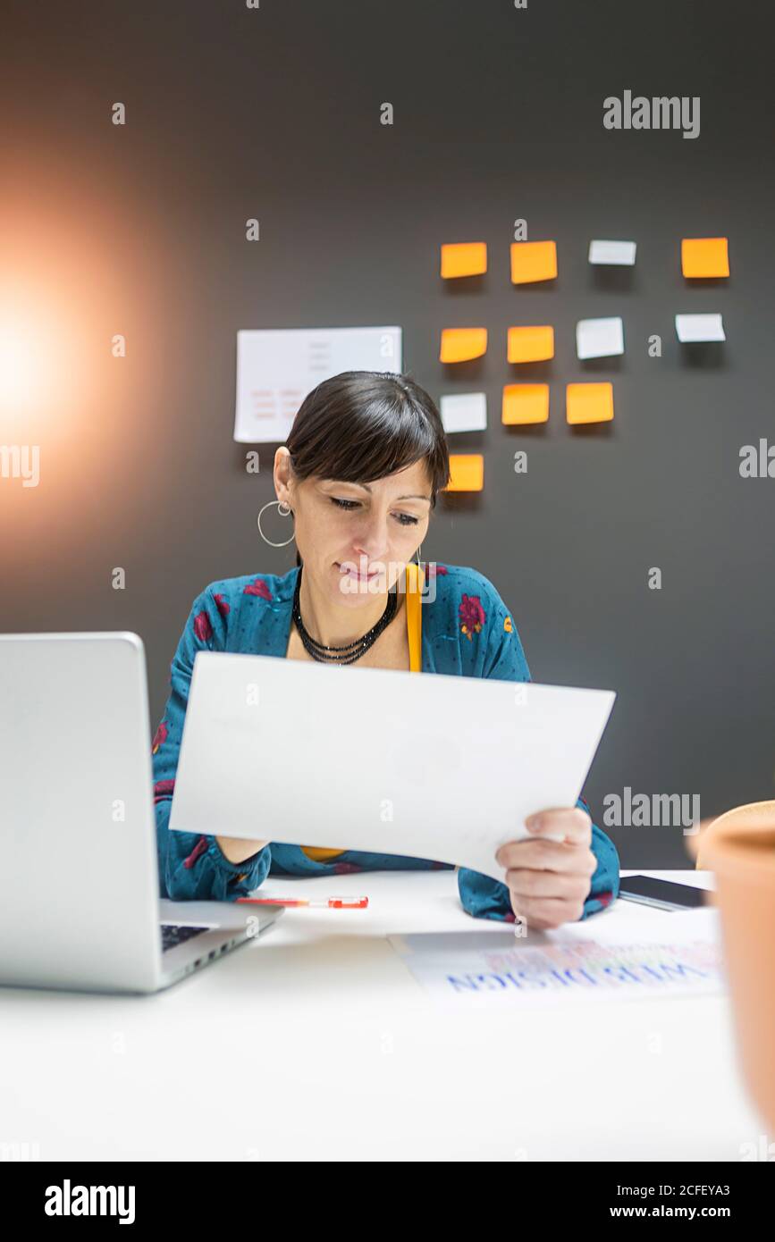 Pretty female working with documents while sitting at desk in modern ...