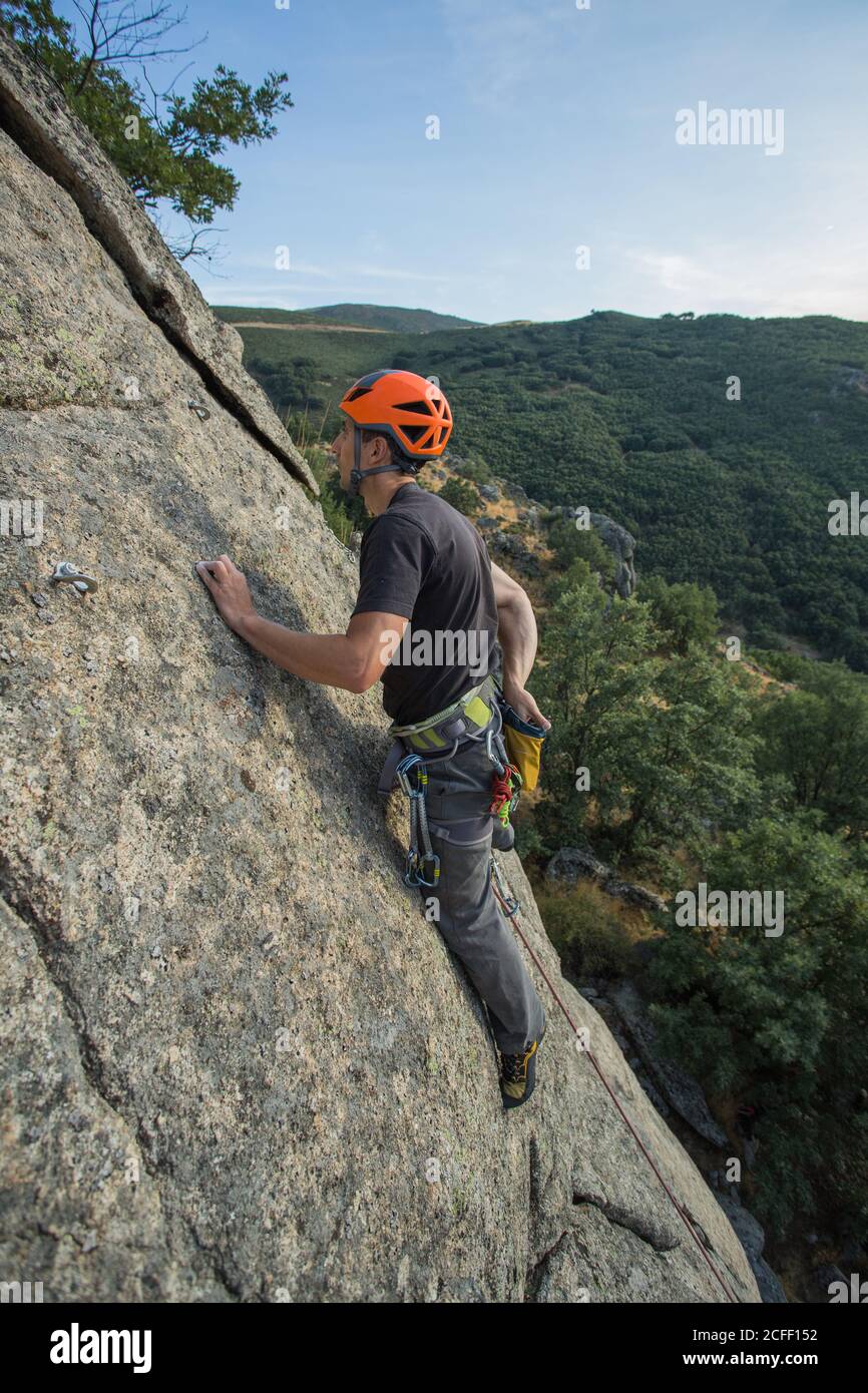 From below man climbing a rock in nature with climbing equipment Stock ...