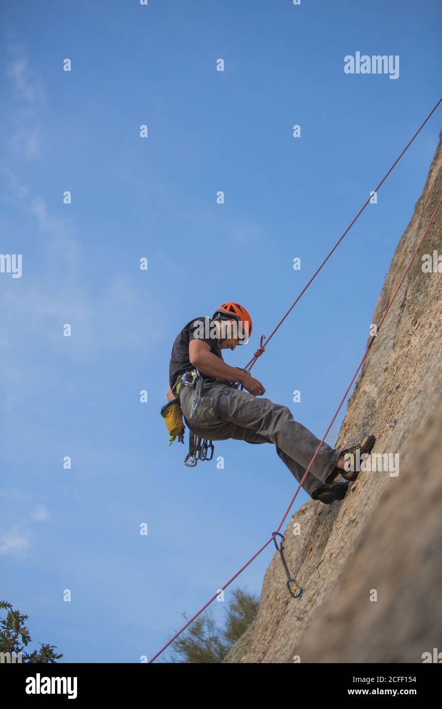From below man climbing a rock in nature with climbing equipment Stock ...