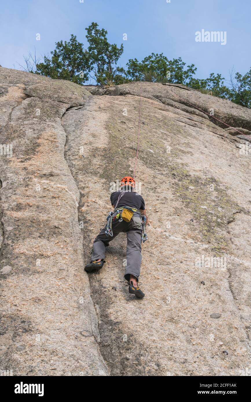 From below anonymous man climbing a rock in nature with climbing ...