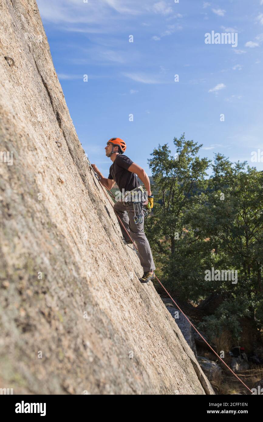 From below man climbing a rock in nature with climbing equipment Stock ...