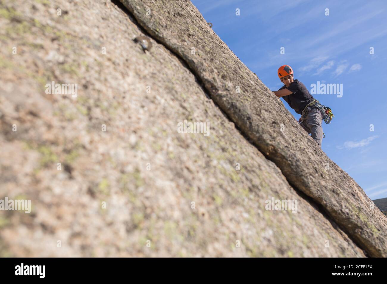 From below man climbing a rock in nature with climbing equipment Stock ...