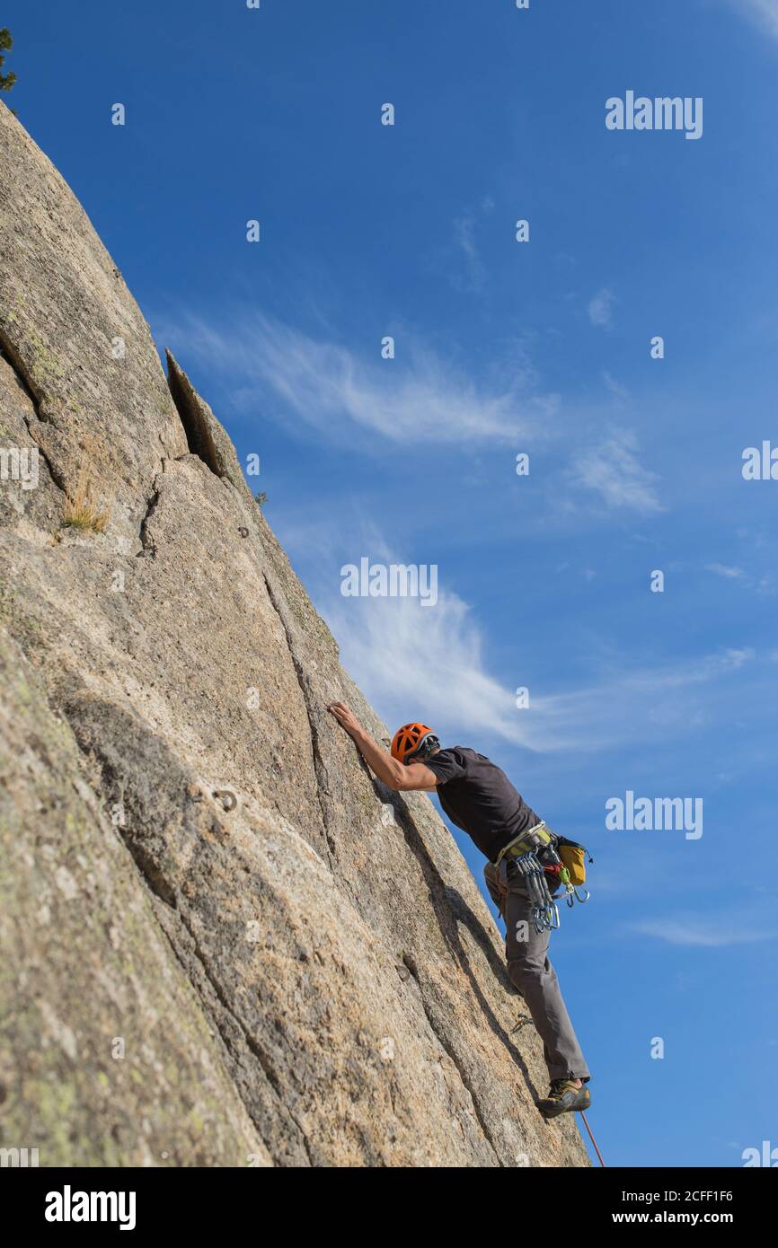 From below man climbing a rock in nature with climbing equipment Stock ...