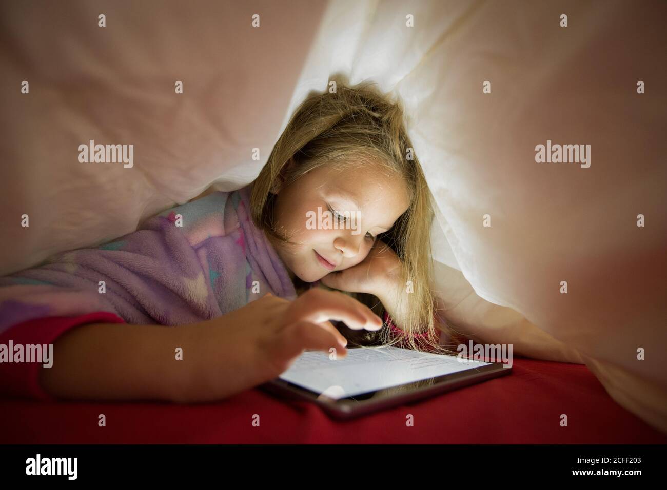 girl using tablet under blanket Stock Photo - Alamy