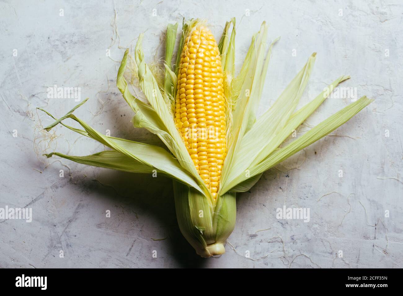 Top view of steps of fresh ripe corn peeling on grey table Stock Photo ...