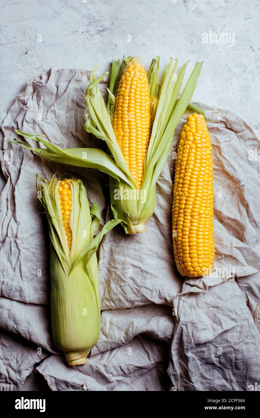 Top view of steps of fresh ripe corn peeling on grey table cloth Stock ...