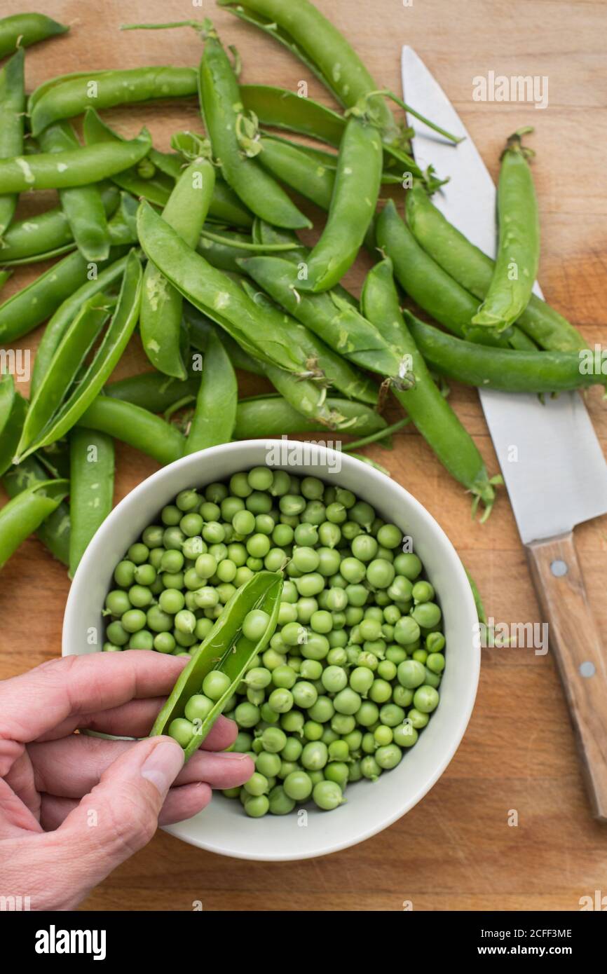 Hands peeling peas with wooden table on the background Stock Photo - Alamy