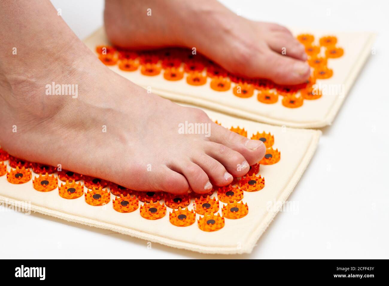 human feet stand on acupuncture mat, close up Stock Photo - Alamy