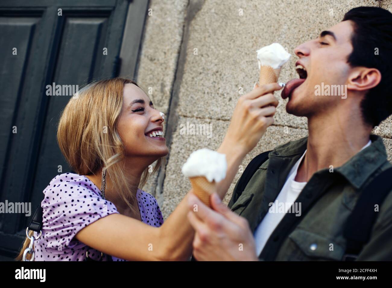 Side view of cheerful young attractive Woman feeding boyfriend by ...