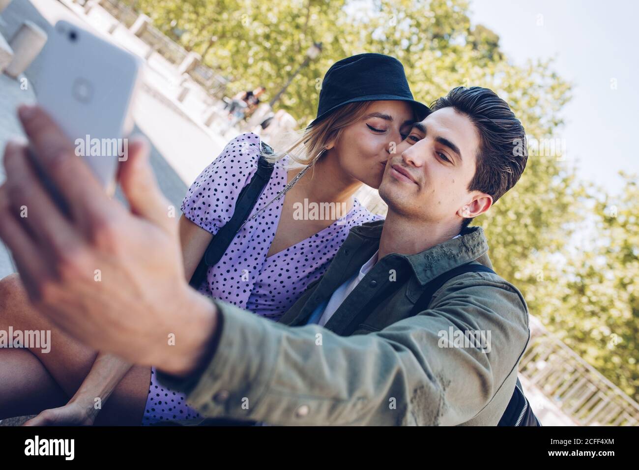 Young handsome man taking photo with girlfriend while kissing in ...