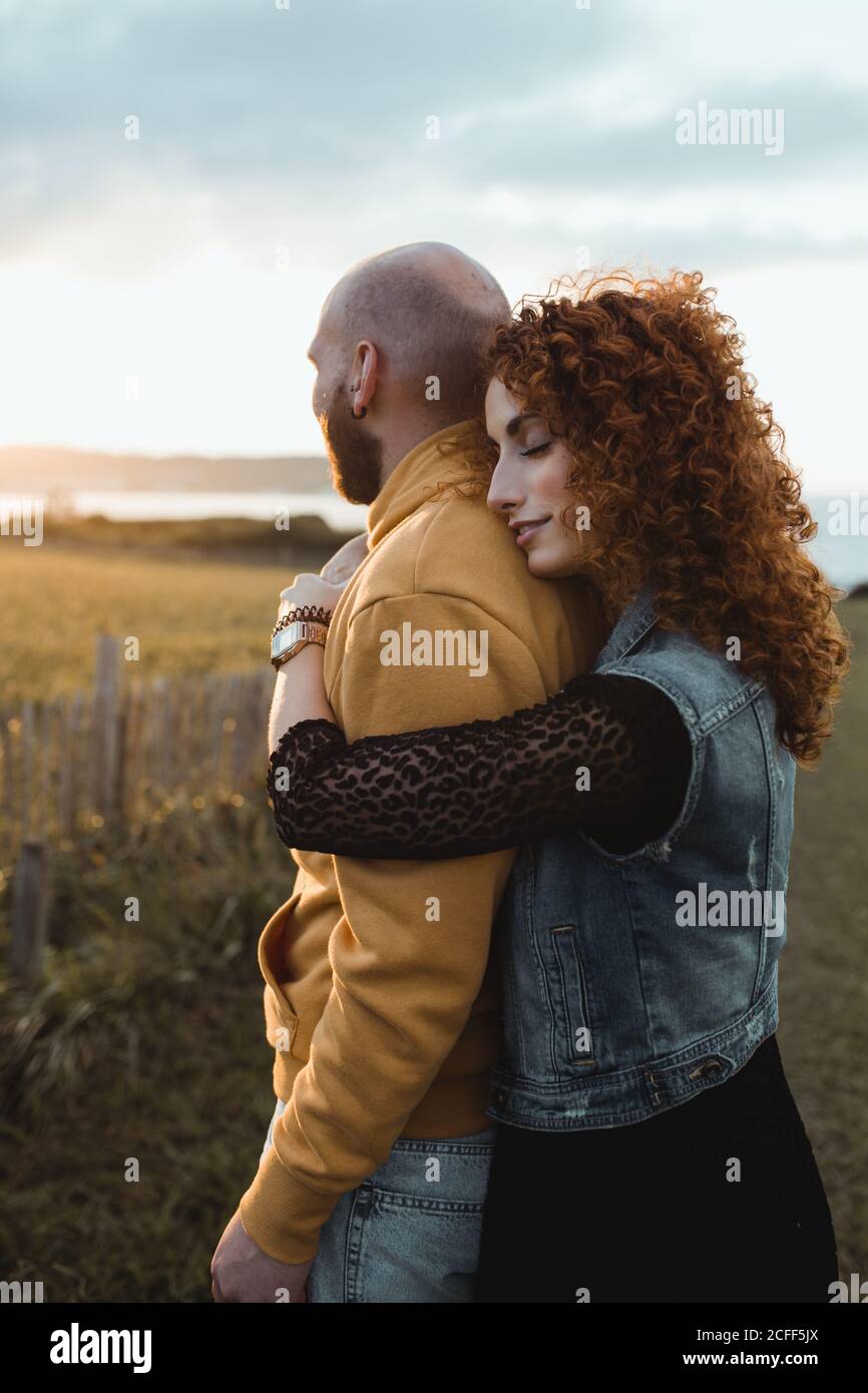 Young bald bearded man in yellow hoodie and jeans shorts being embraced ...