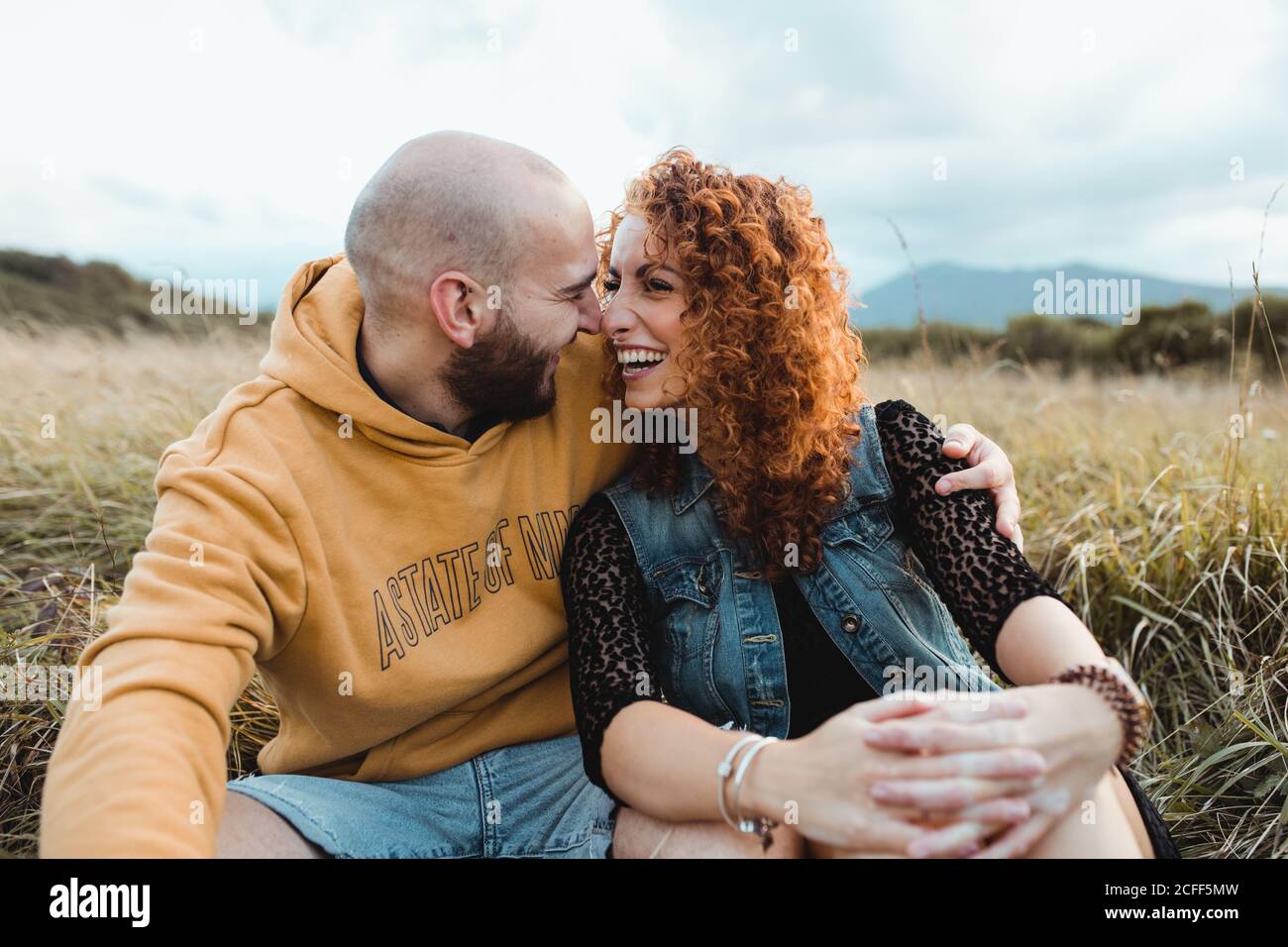 Young bald bearded man in yellow hoodie and jeans shorts embracing ...