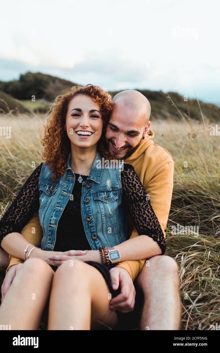 Young bald bearded man in yellow hoodie and jeans shorts embracing ...