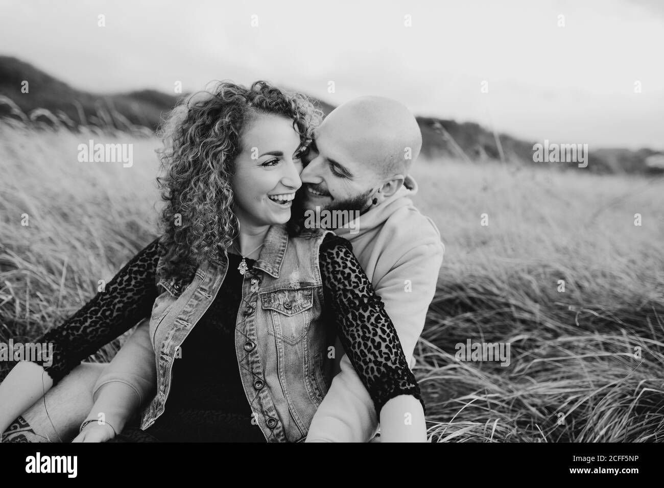 Young bald bearded man in yellow hoodie and jeans shorts embracing ...