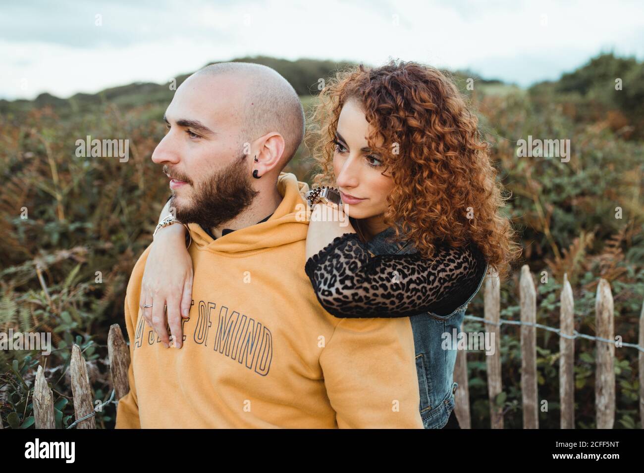 Young bald bearded man in yellow hoodie and jeans shorts embracing ...