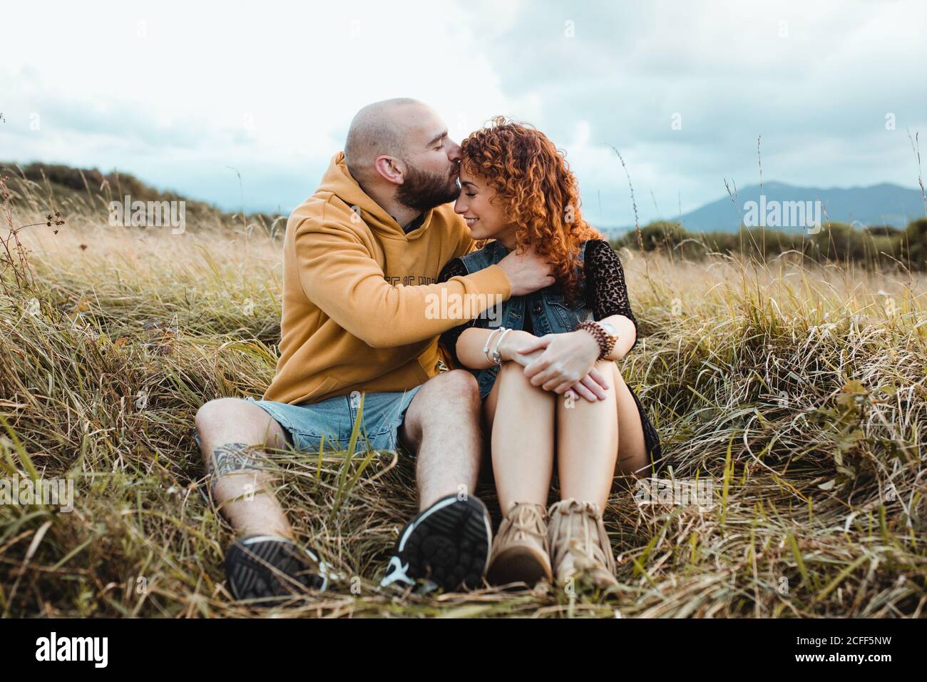 Young bald bearded man in yellow hoodie and jeans shorts embracing ...