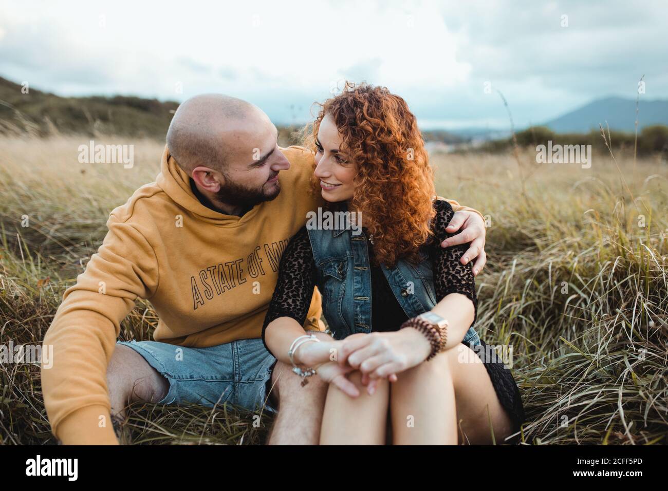 Young bald bearded man in yellow hoodie and jeans shorts embracing ...