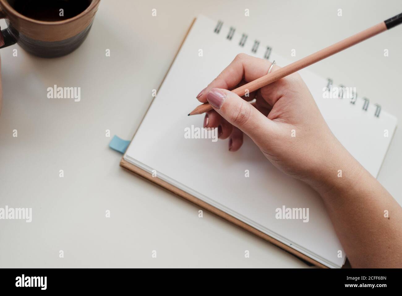 Crop from above view of unrecognizable Woman taking notes with pencil ...