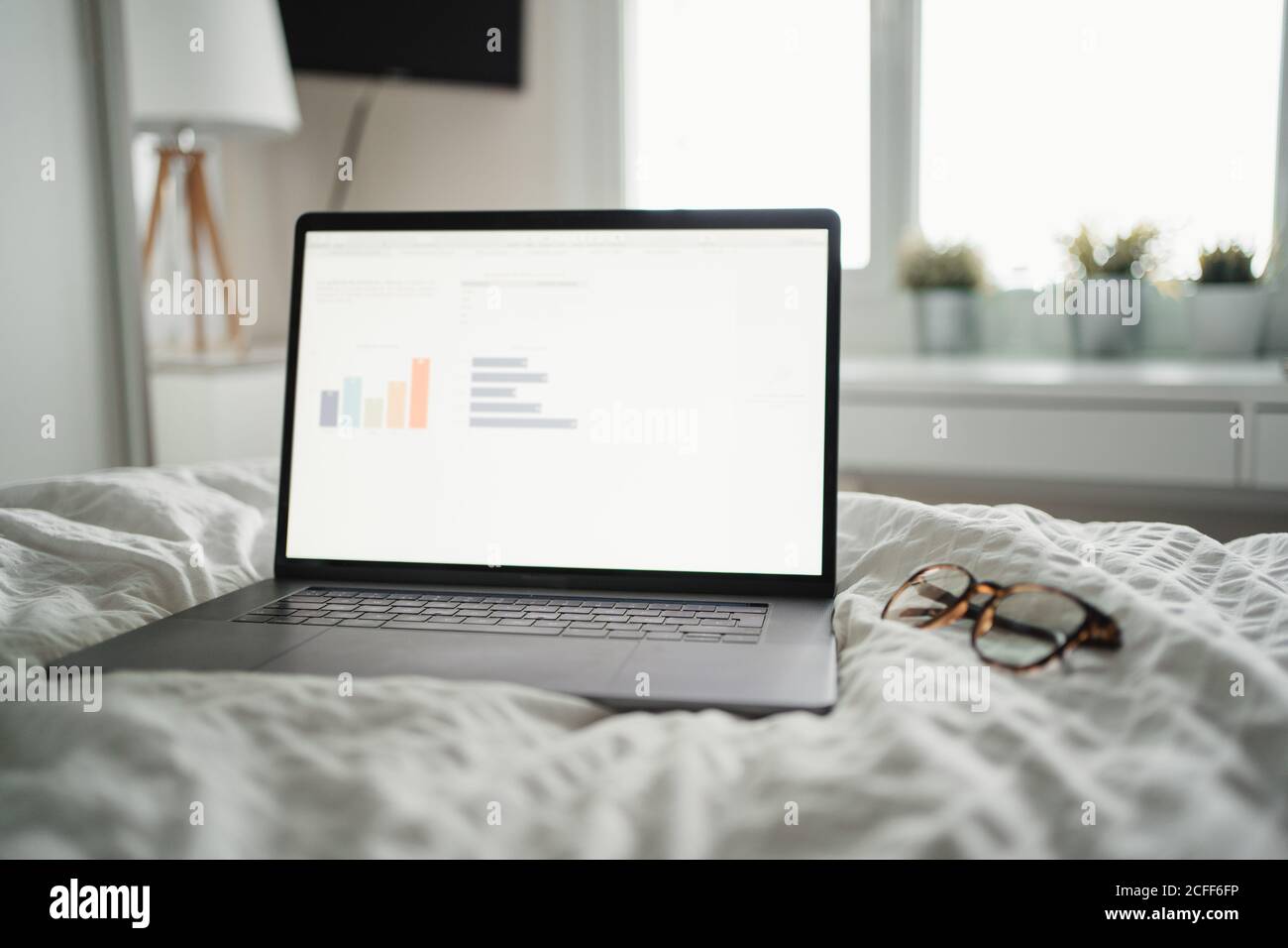 Opened computer with diagrams on screen and spectacles on on bed in ...