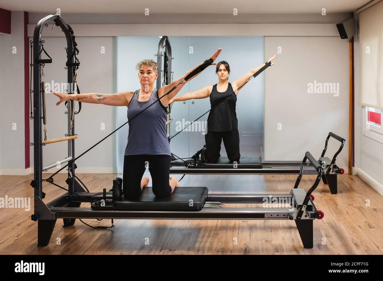 Sportswomen in activewear doing exercises on pilates machine and ...