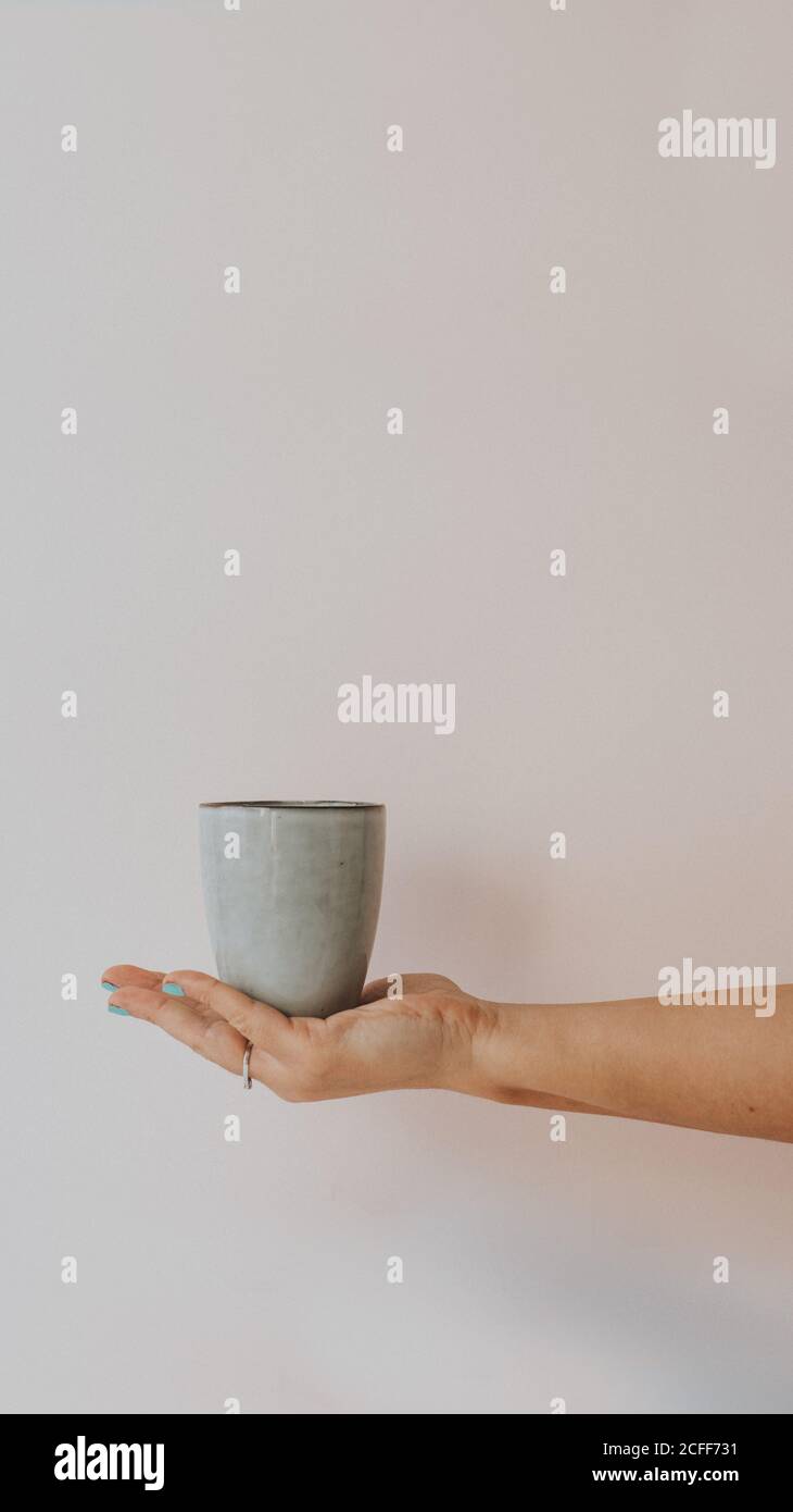 Large gray mug with drink in hand of crop person on white background ...