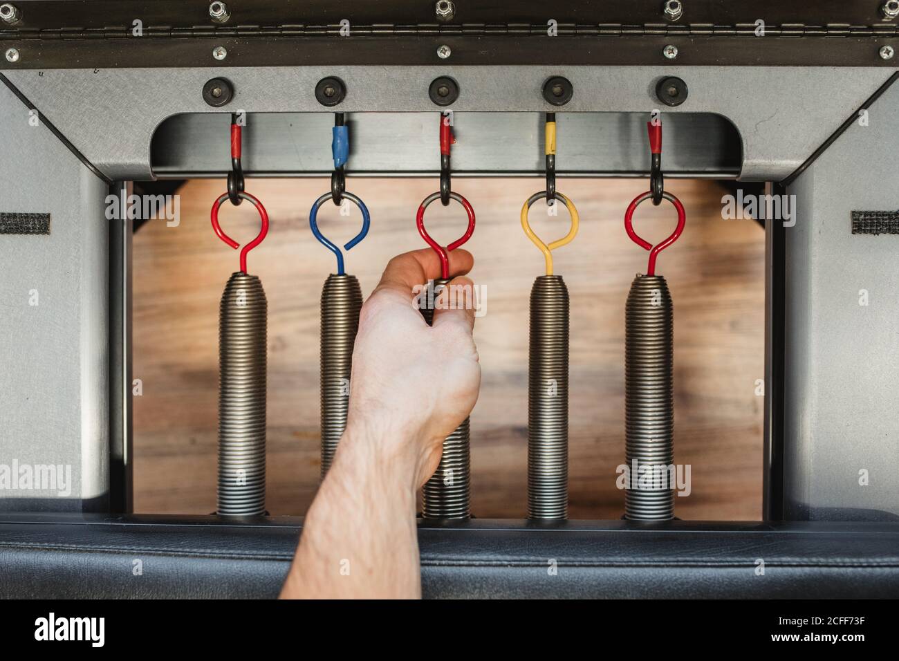 Crop man touching metal springs on hooks of modern pilates reformer ...
