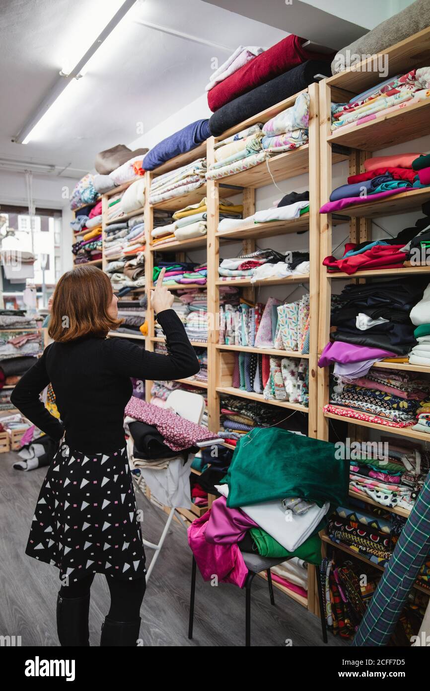 Back view of anonymous adult Woman rummaging through shelf while ...
