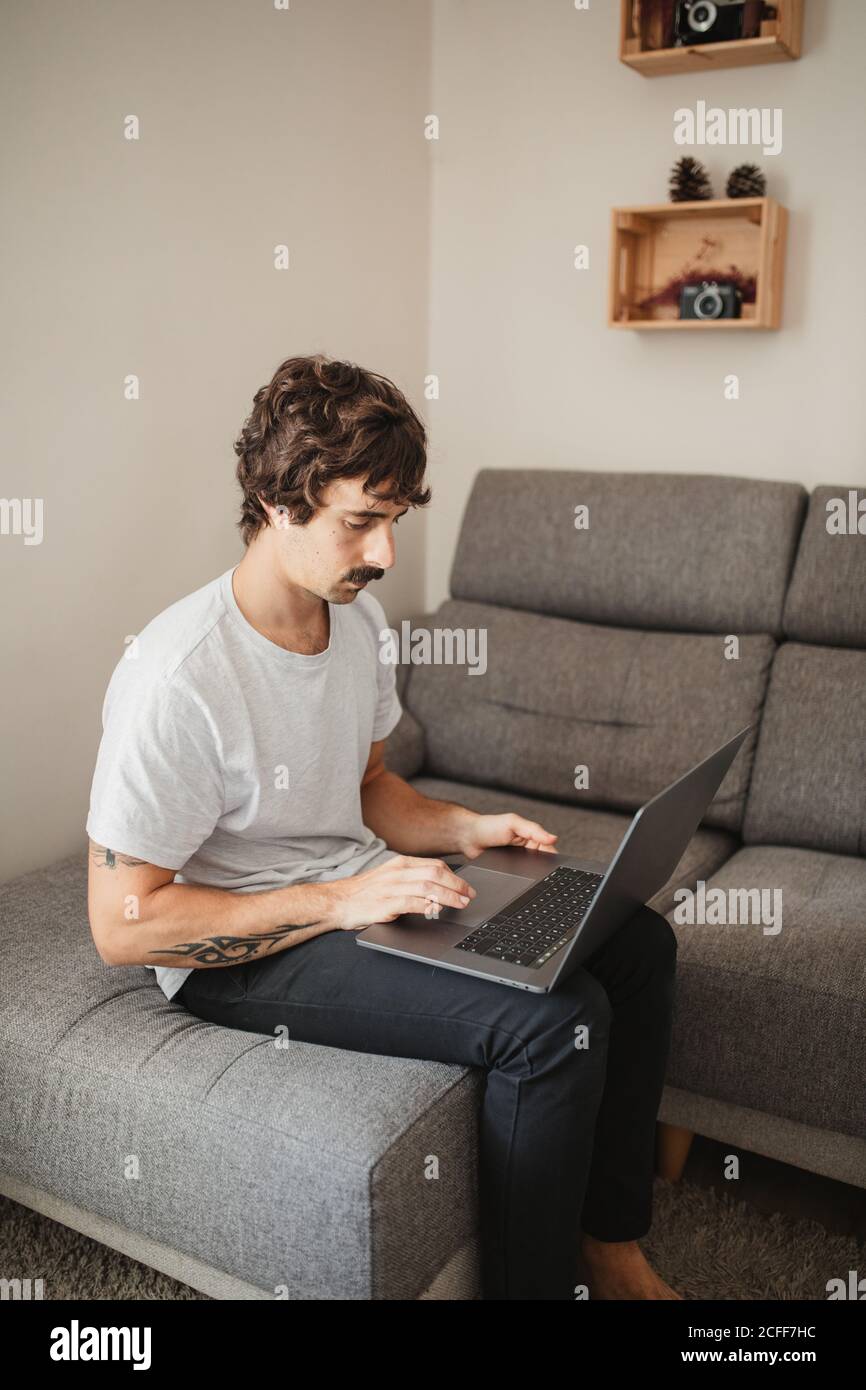Side view of concentrated male entrepreneur using laptop while working ...