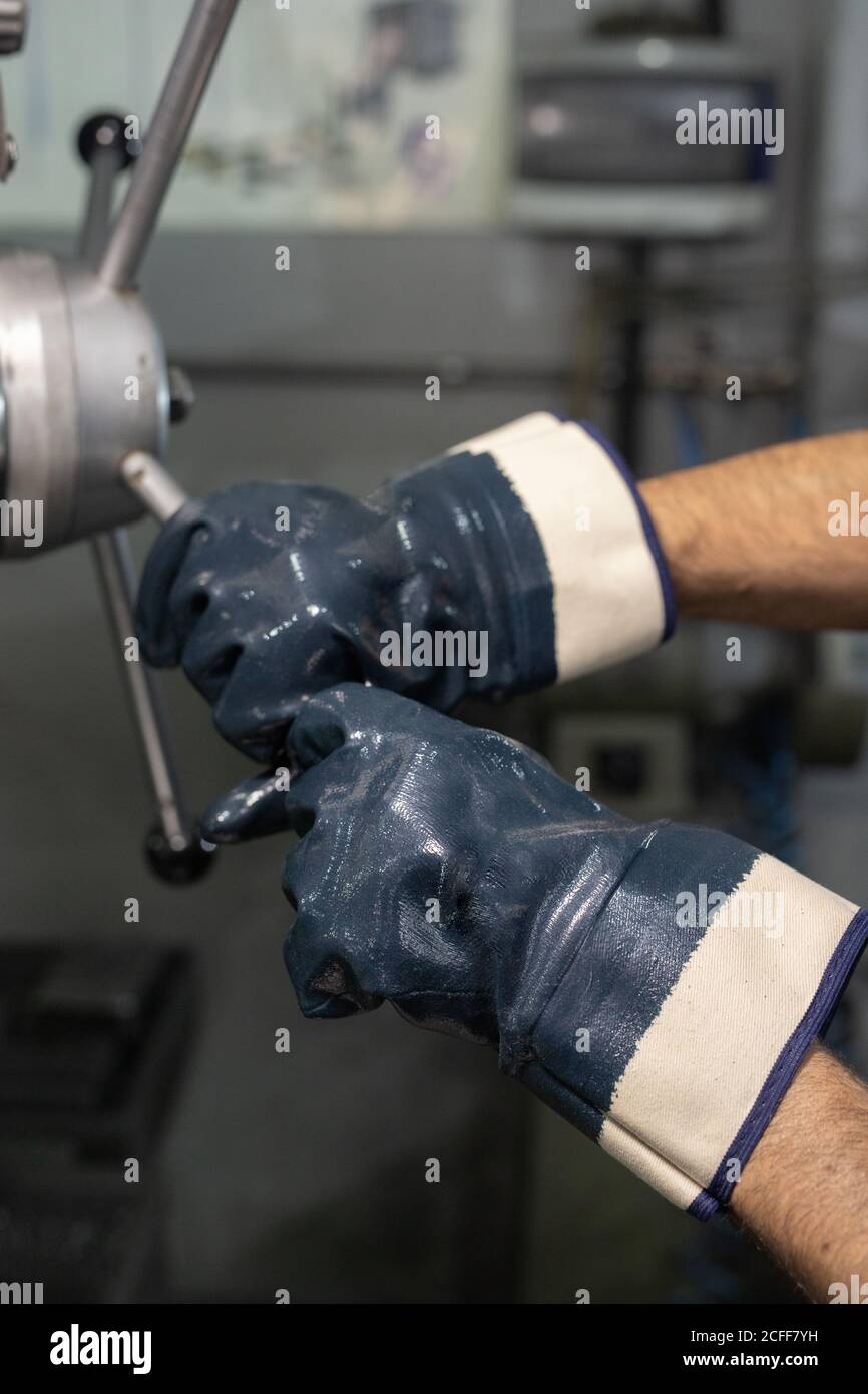 Crop unrecognizable male master in rubber gloves turning industrial ...