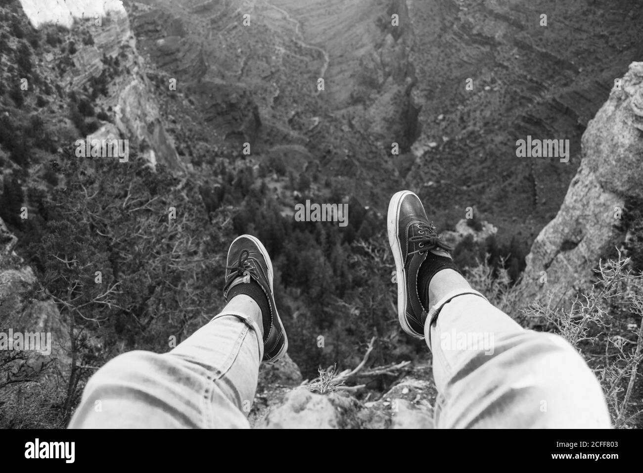 From above of faceless guy in casual wear sitting on top of rock in ...
