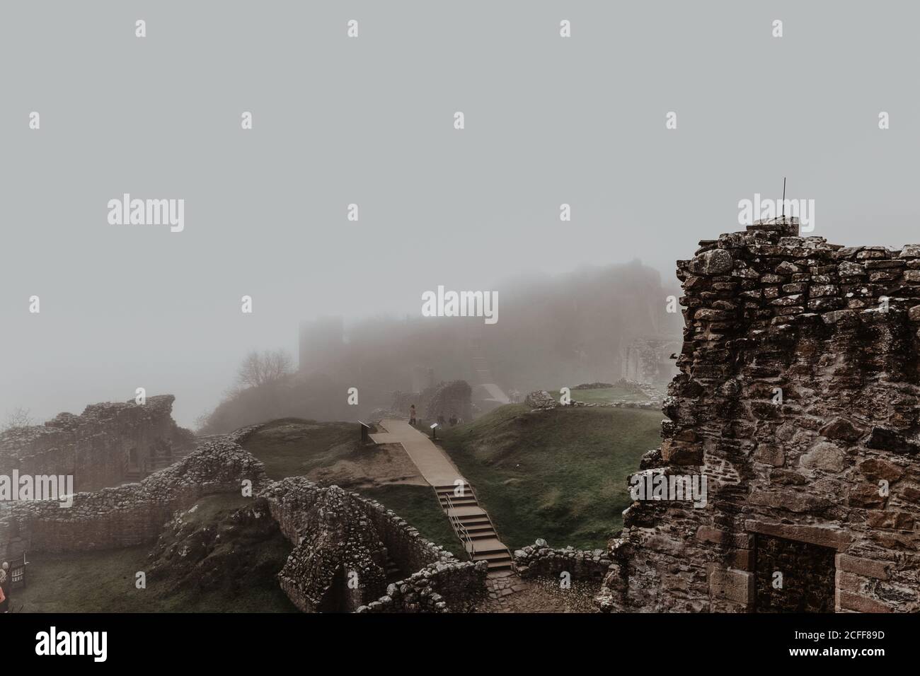 Destroyed old stone castle with fog with walls and stairs with tower on ...