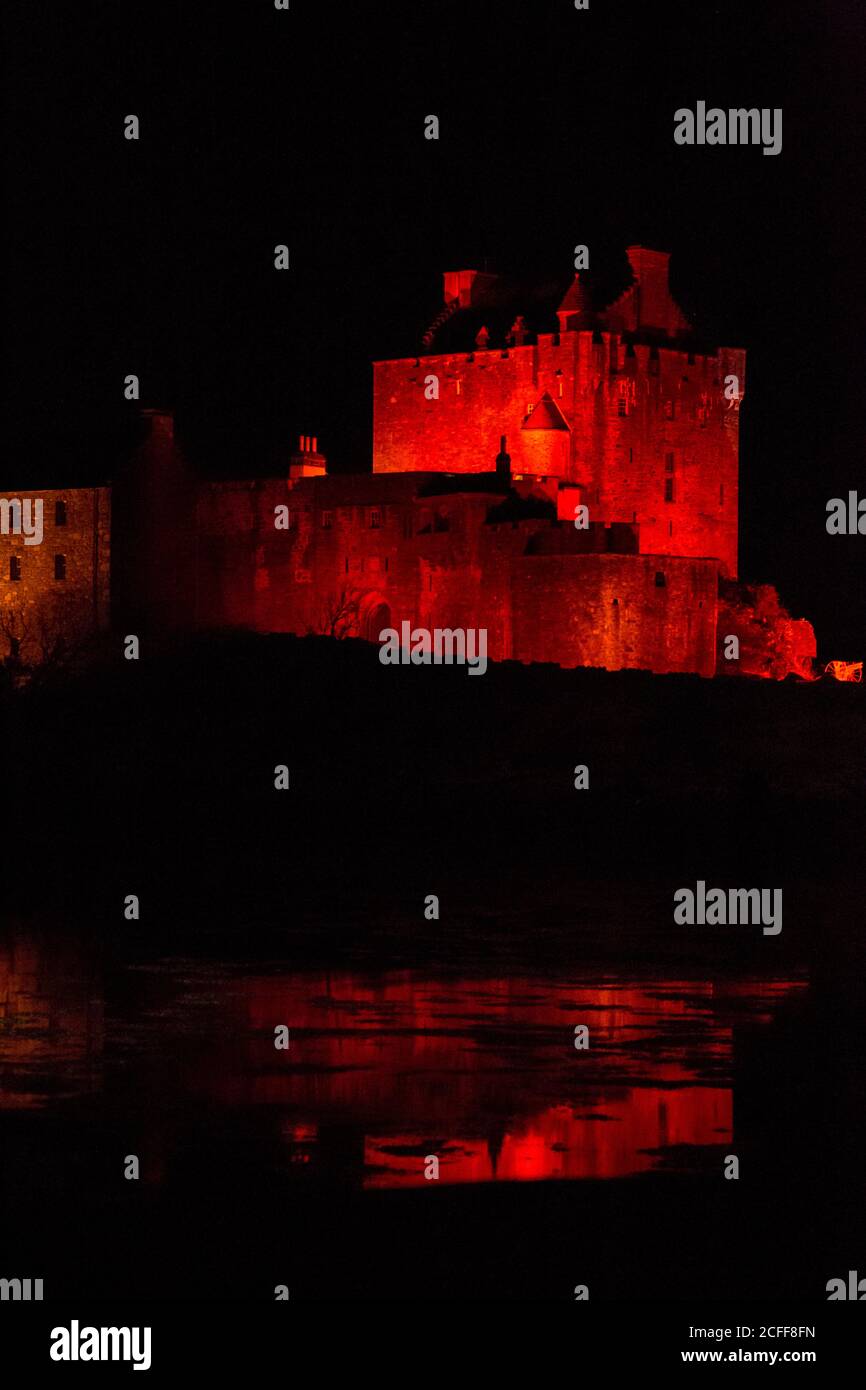 Night landscape of old majestic castle on river bank illuminated by red ...
