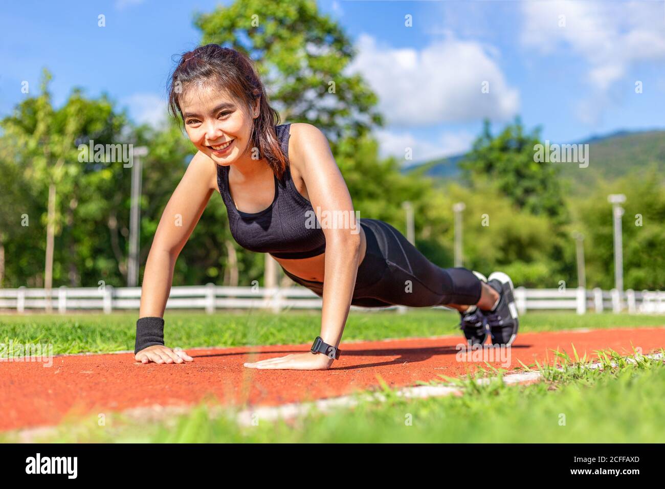 Happy beautiful young Asian woman doing push up exercise in the morning ...