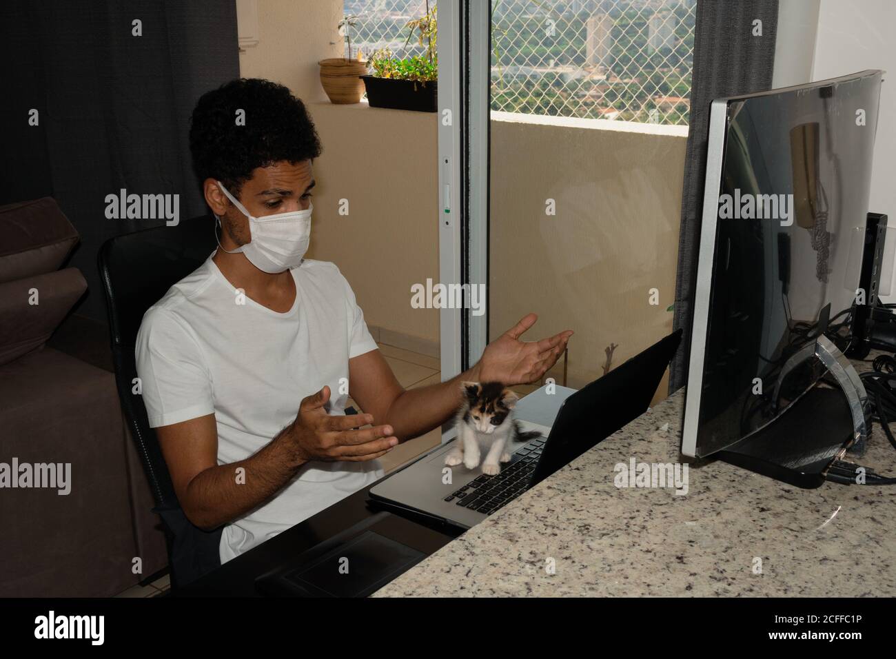 Black man at computer desk wearing pandemic mask with kitten Stock ...