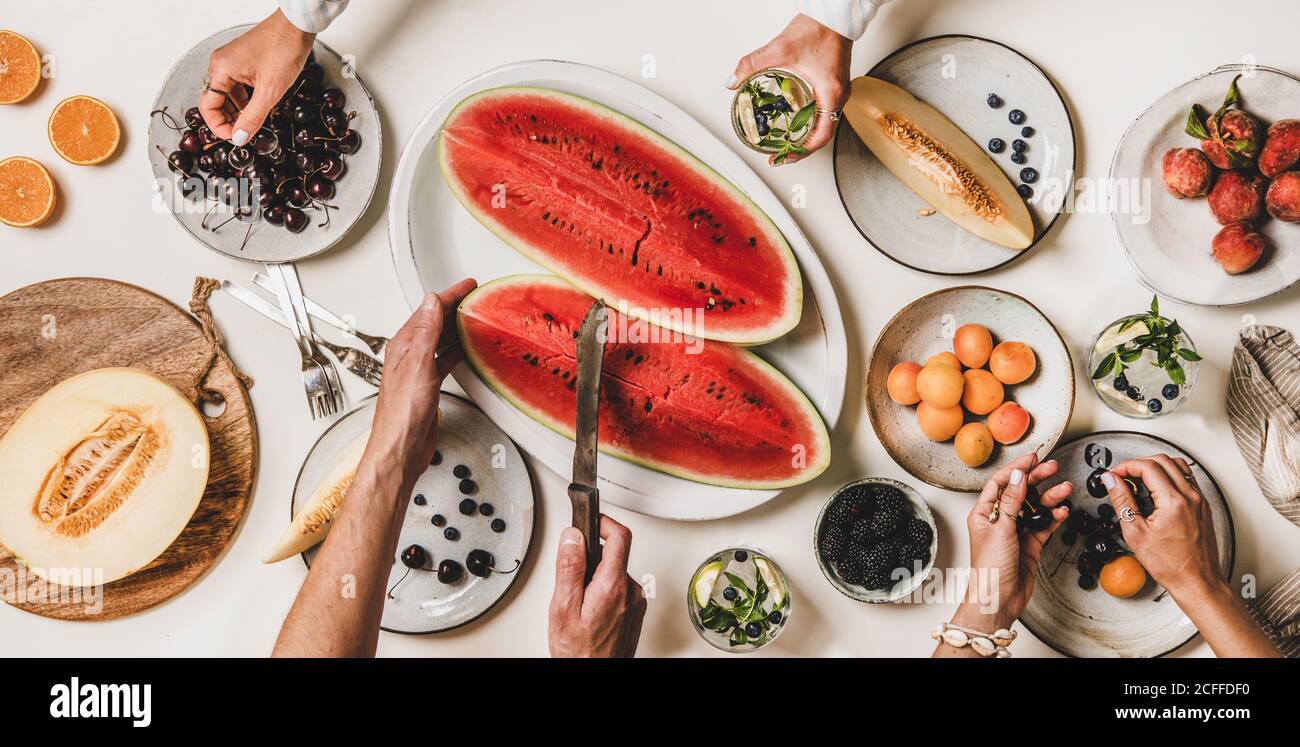Flat-lay of peoples hands taking food from tropical fruit lunch Stock ...