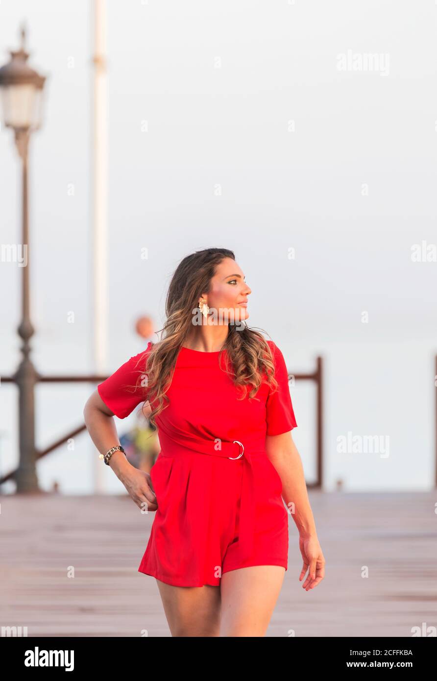 Cheerful attractive Woman in beach robe walking near beach in evening ...