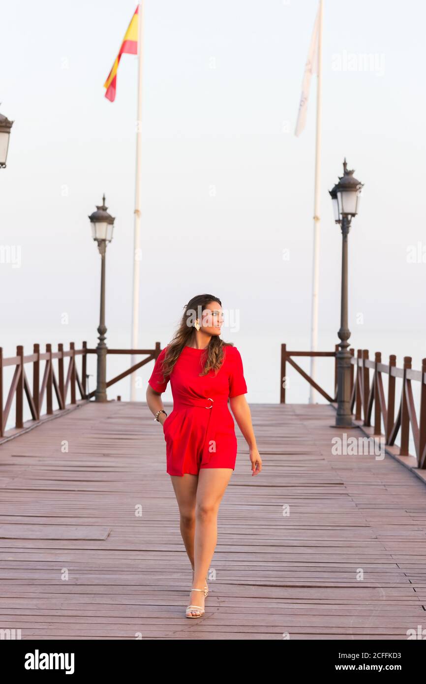 Cheerful attractive Woman in beach robe walking near beach in evening ...