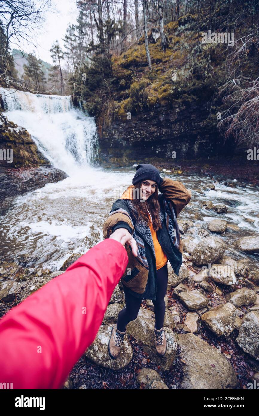 Crop view of Woman in warm clothes walking and holding hand of person ...