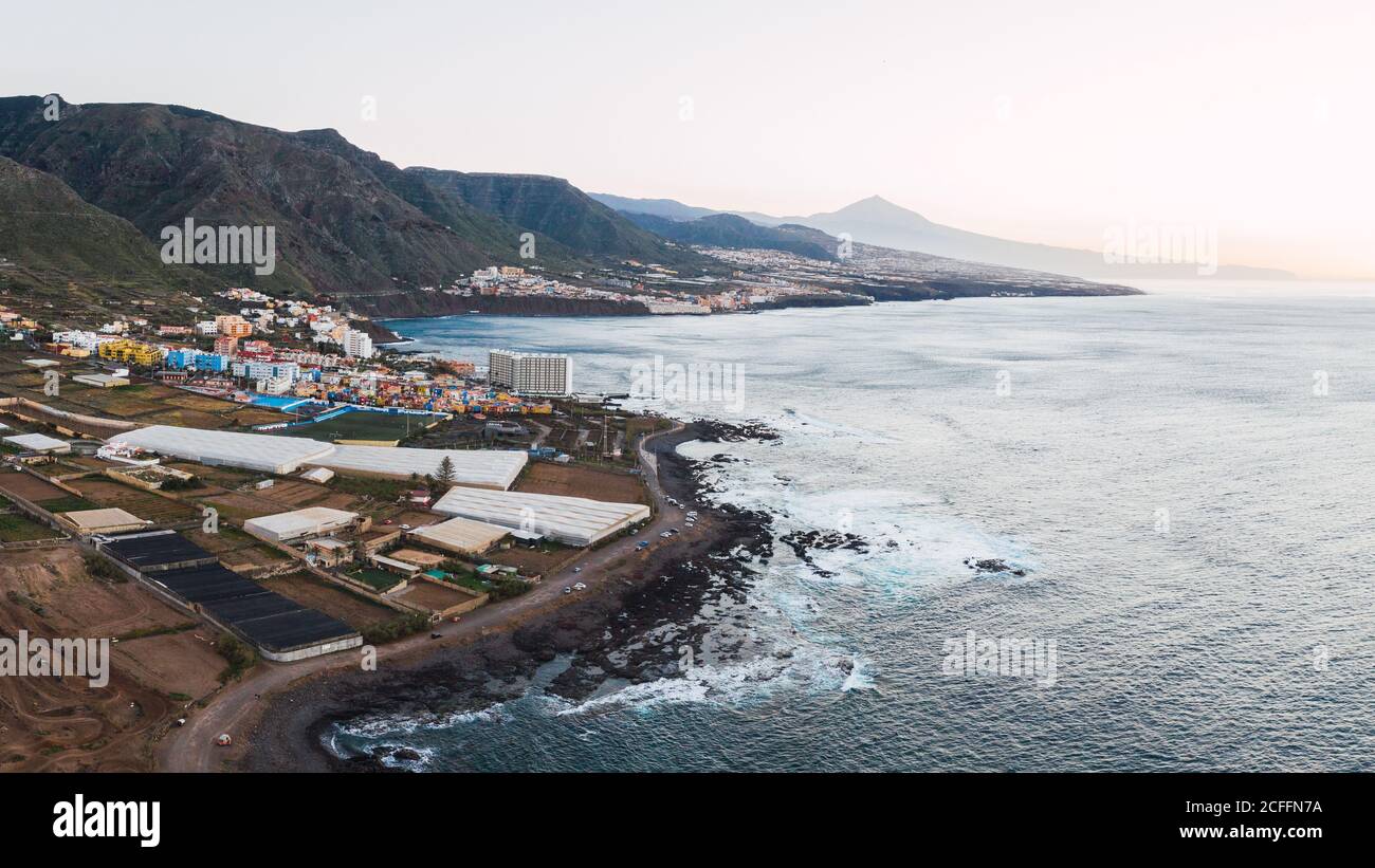 Aerial view of cityscape on majestic coastline at bottom of mountains ...