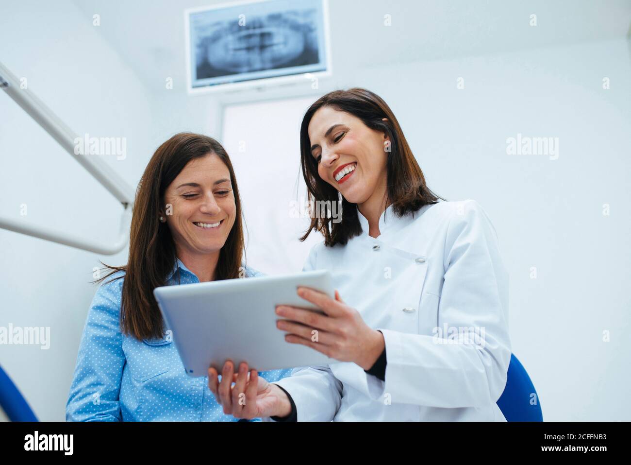 Dentist speaking with client showing document with information Stock ...