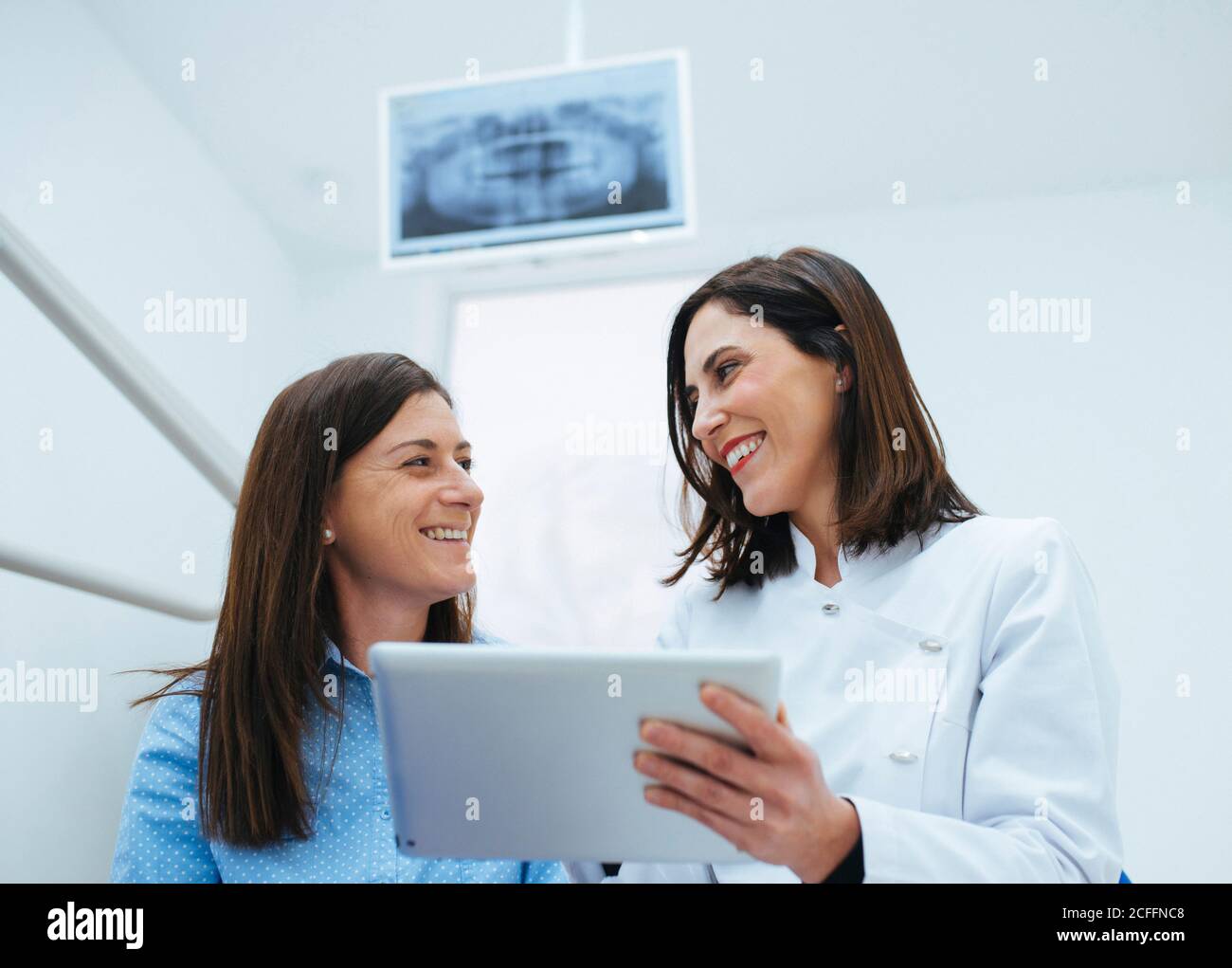 Dentist speaking with client showing document with information Stock ...