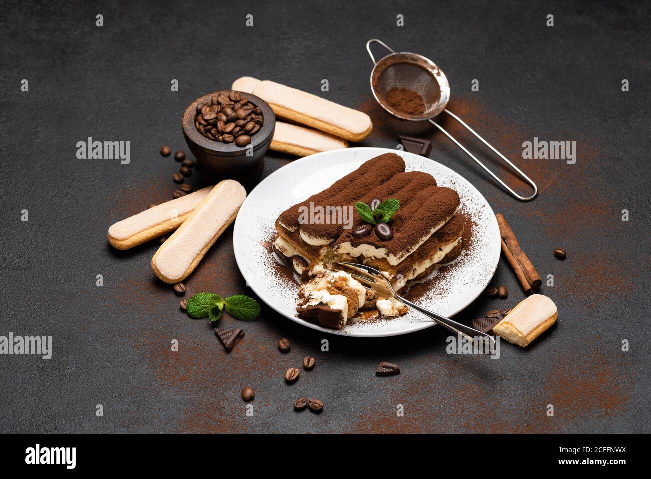 portion of Classic tiramisu dessert and savoiardi cookies on concrete ...