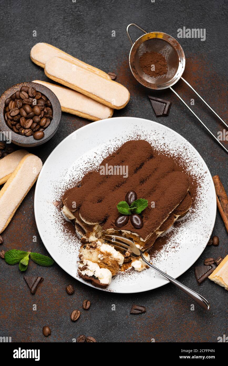 portion of Classic tiramisu dessert and savoiardi cookies on concrete ...