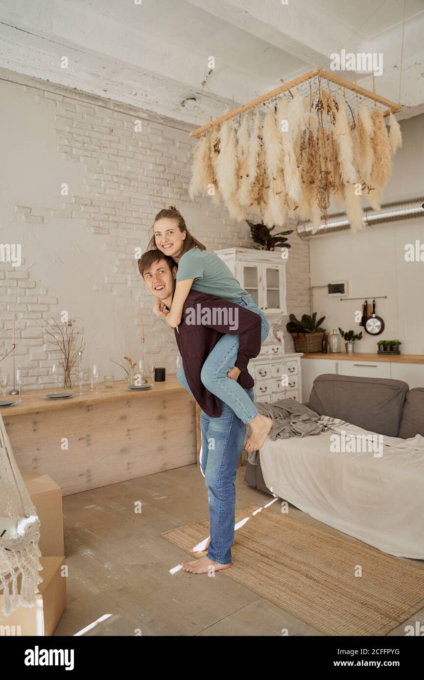 Side view of smiling handsome guy giving piggyback ride to cheerful ...