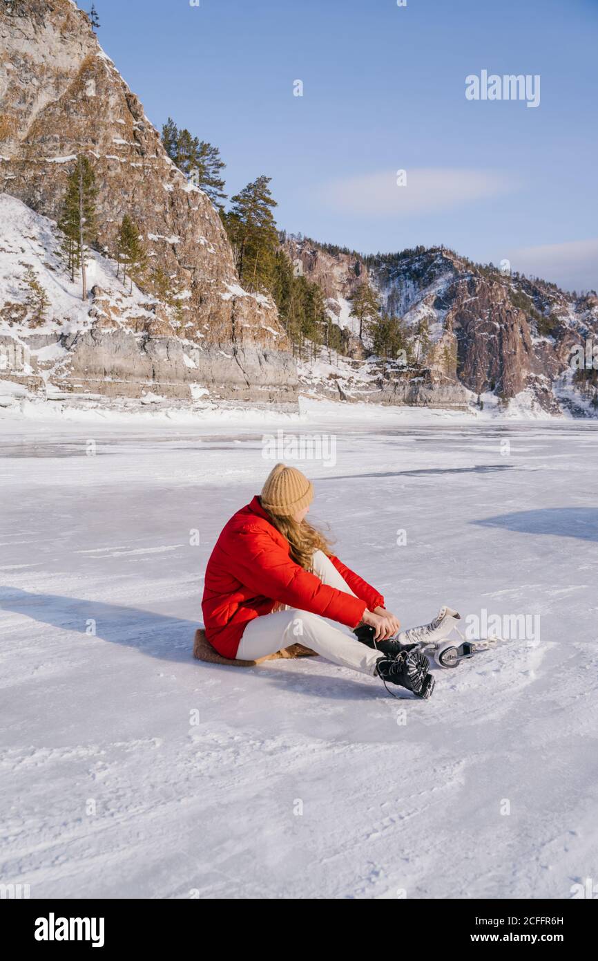 Woman sitting on snow and changing boots Stock Photo - Alamy