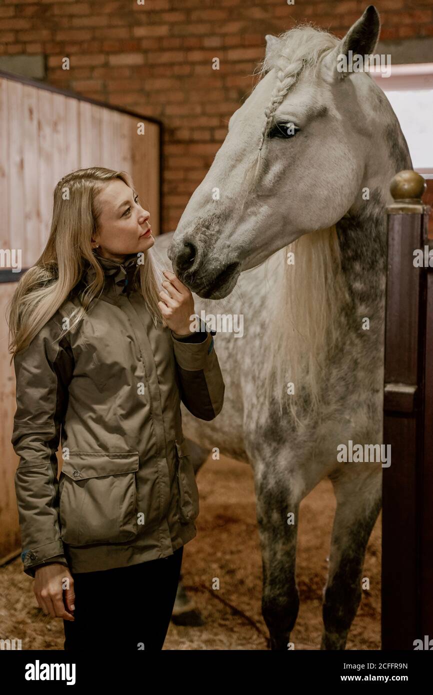 Side view of long haired warm dressed blonde Woman giving food to ...