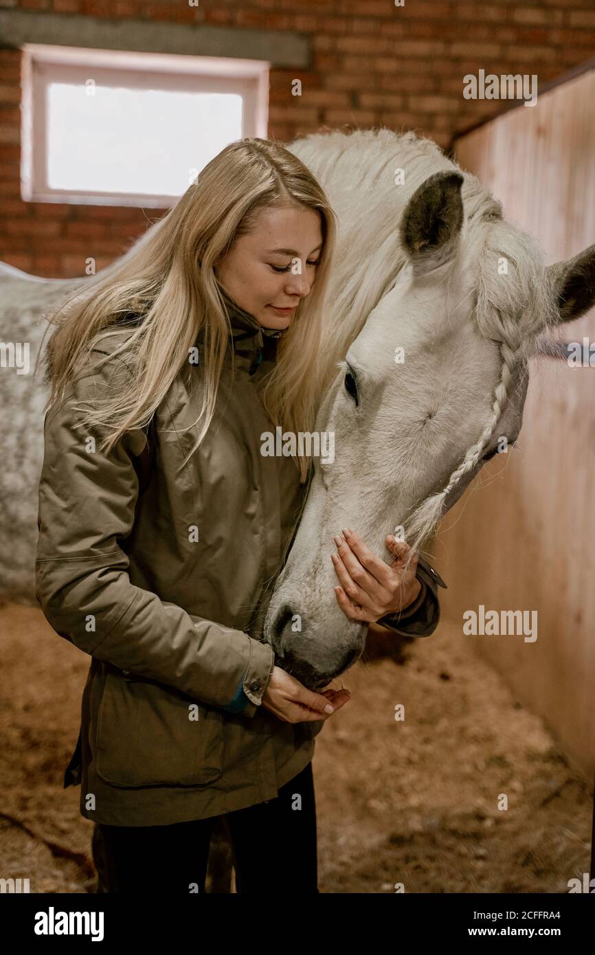 Side view of long haired warm dressed blonde Woman giving food to ...