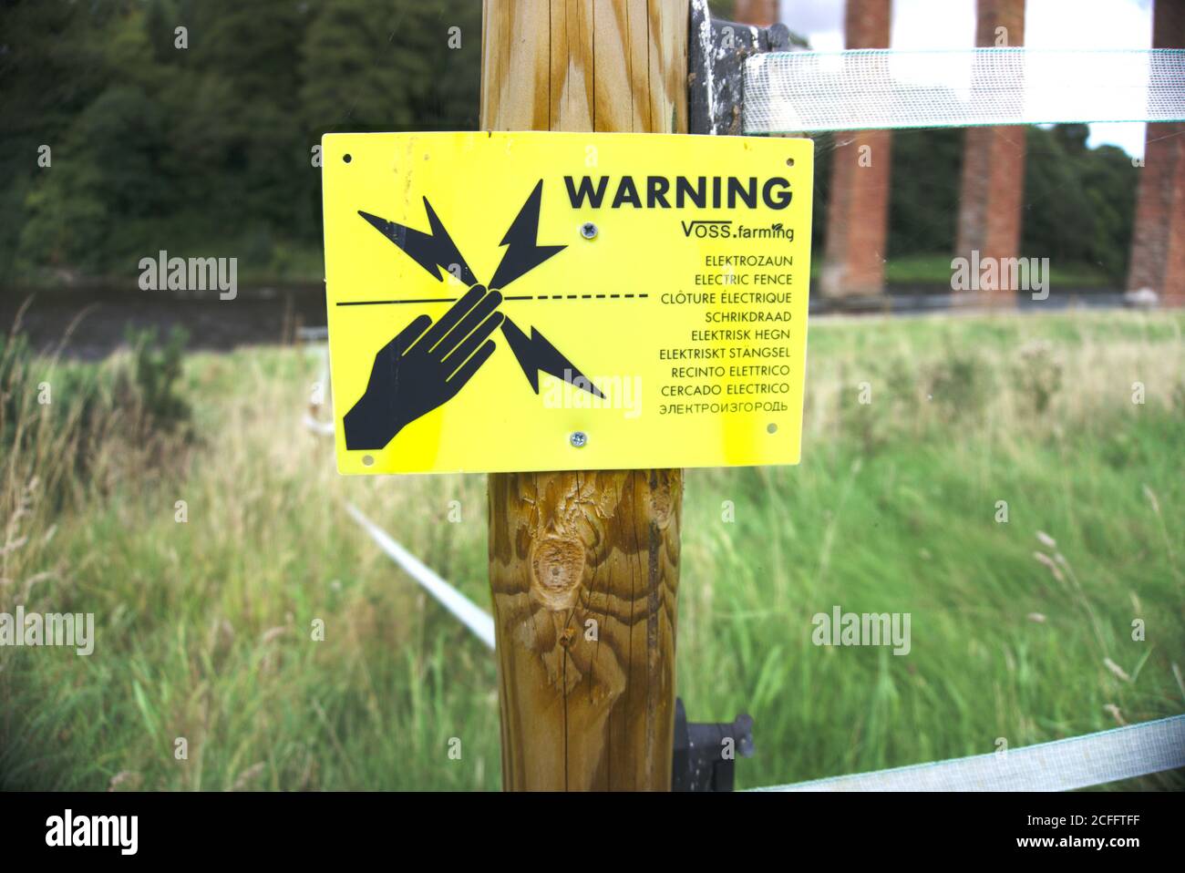 Electric fence warning sign in multiple languages next to River Tweed ...